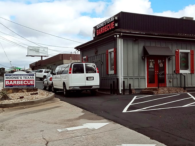 The unassuming gray exterior with bold red signage is like a secret handshake – those who know, know. BBQ paradise awaits inside.