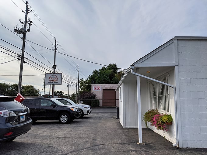 The unassuming white exterior of Fred's Diner stands like a culinary speakeasy – no flash, all substance, with flower baskets offering the only hint of the warmth inside.