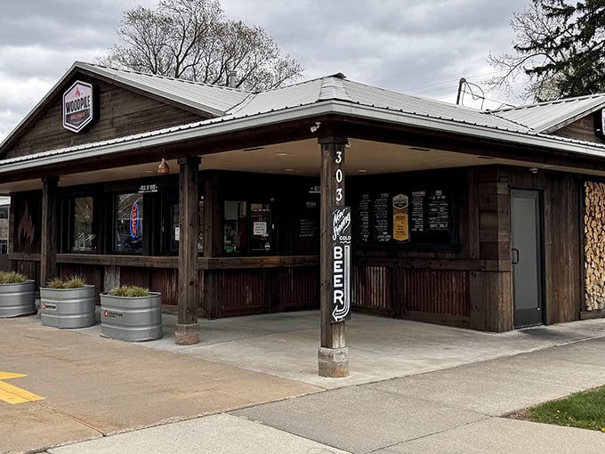 The rustic wooden exterior of Woodpile BBQ Shack promises no pretension—just serious smoke business happening inside those walls.