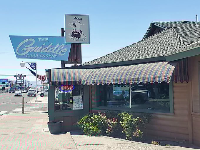 The blue vintage sign beckons like an old friend, promising "Good Cookin'" beneath Nevada's endless sky—a roadside oasis for hungry travelers.