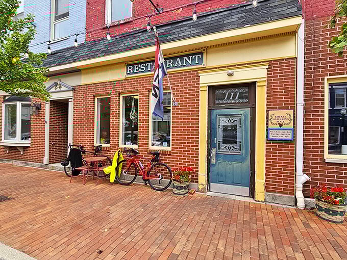 The classic brick façade and blue door of Liberty Gathering Place whispers "come on in" like a small-town welcome committee with better food.