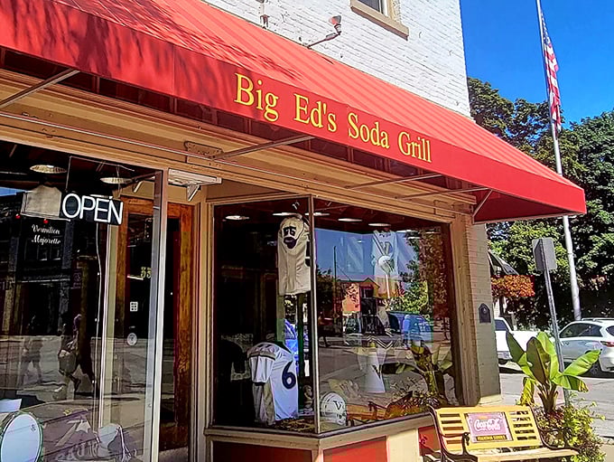 "Big Ed's Soda Grill" glows in golden letters against that classic red awning—a beacon for hungry travelers and nostalgic locals alike.