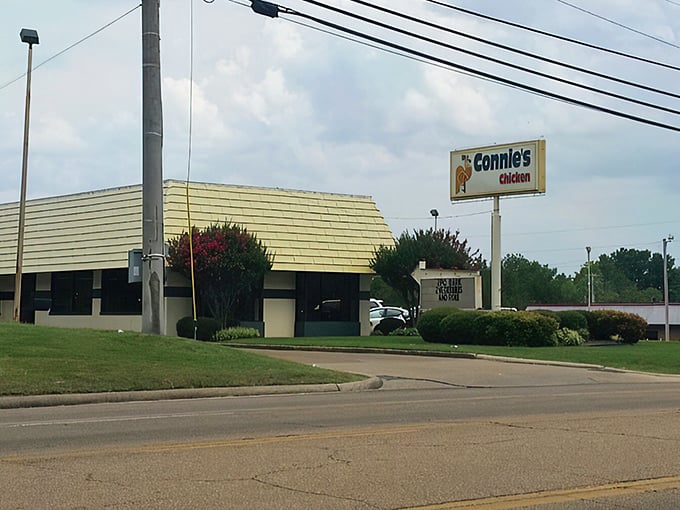 The unassuming yellow-roofed exterior of Connie's Chicken stands like a beacon of culinary promise along Tupelo's roadway, hiding delicious secrets within.