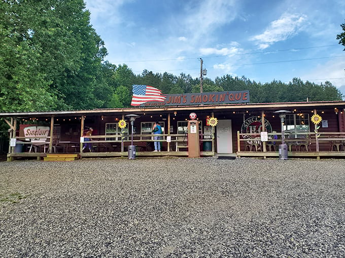 The American flag waves proudly above Jim's Smokin' Que, where that vintage gas pump isn't just decoration—it's a promise of old-school authenticity.