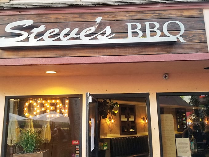 The wooden sign beckons like an old friend – Steve's BBQ in Whittier promises smoky treasures behind that glowing "OPEN" sign.