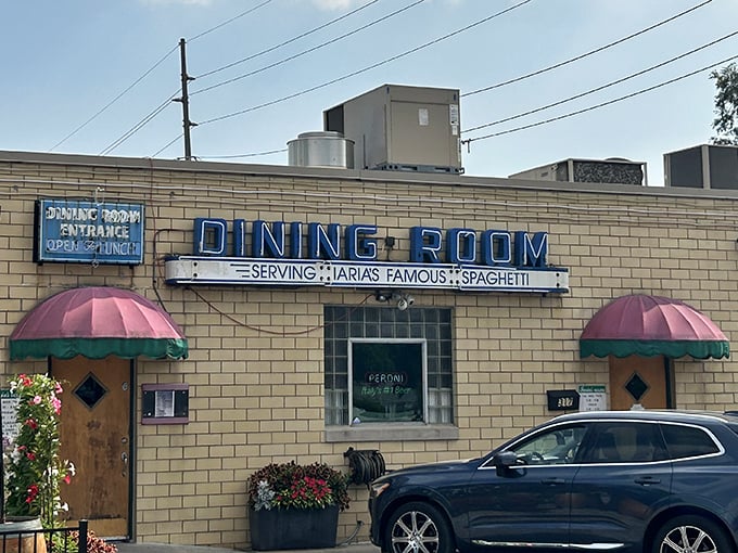 The iconic blue "DINING ROOM" sign has welcomed hungry Hoosiers since 1933, promising Italian comfort beneath those cheerful pink and green awnings.