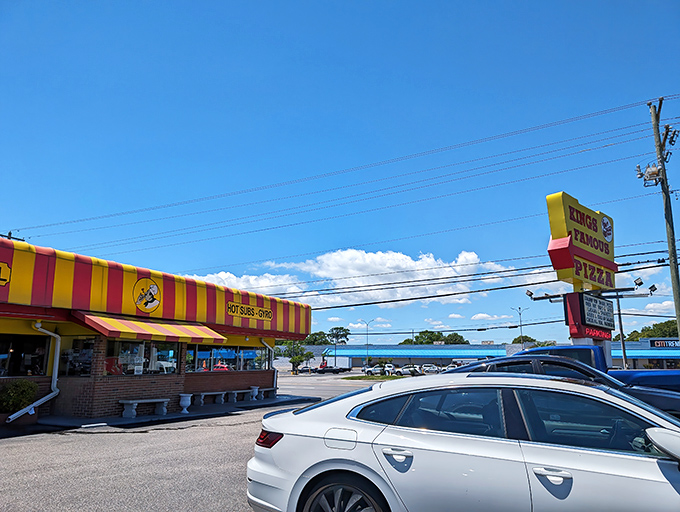 The unmistakable red and yellow awning of King's Famous Pizza stands out against the Carolina blue sky, beckoning hungry beachgoers like a delicious lighthouse.