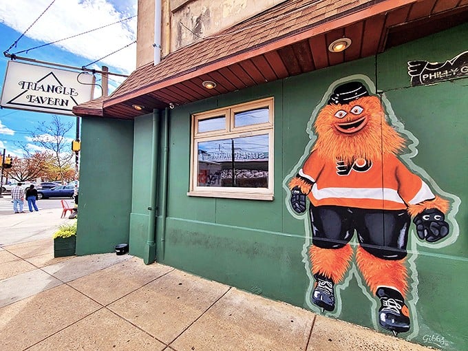 Gritty, Philadelphia's beloved orange mascot, stands guard outside Triangle Tavern – a quirky sentinel promising good times and great wings within.