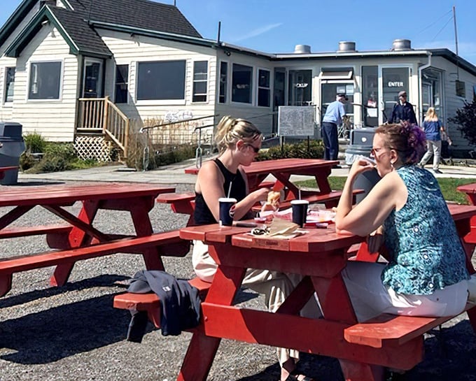 Diners enjoying the simple pleasure of fresh seafood at red picnic tables – the Maine equivalent of five-star dining.