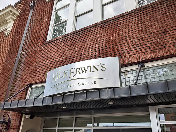 The iconic brick façade of Rick Erwin's West End Grille—where Greenville's culinary dreams come true beneath that elegant silver signage.