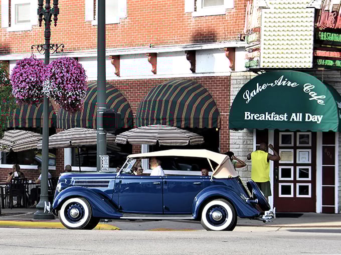Classic Americana meets breakfast heaven – a vintage convertible cruises past Lake Aire's inviting green awnings and vibrant hanging flower baskets, promising comfort food and small-town charm.