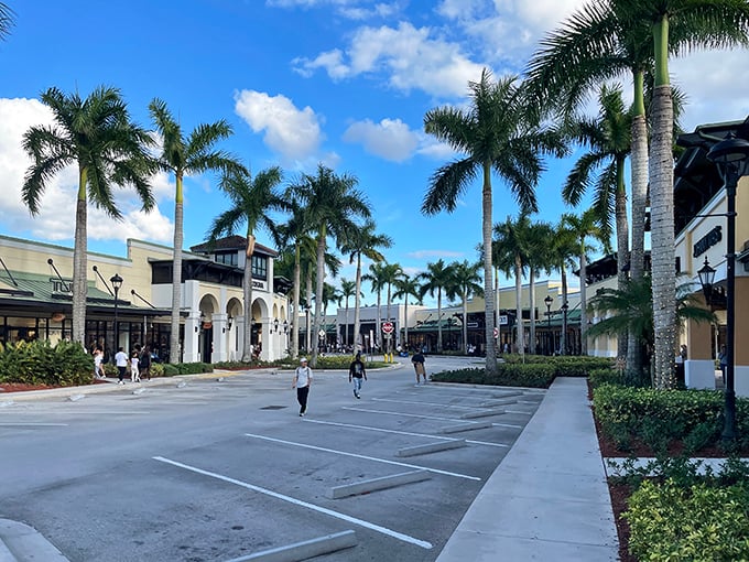 Palm trees standing like elegant sentinels, guiding shoppers to Mediterranean-inspired storefronts where bargains await beneath Florida's impossibly blue sky.