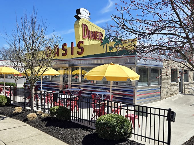 The gleaming yellow and chrome exterior of Oasis Diner stands like a time capsule on Plainfield's main drag, complete with those cheerful umbrellas promising shade and satisfaction.