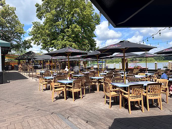 The outdoor dining area at Lord Fletcher’s offers a stunning view of the lake, where stone and cedar accents create a rustic charm that feels like an old friend waiting with a cold drink and warm stories.