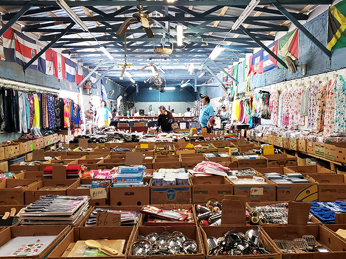 Inside OBT Flea Market, where treasure hunting becomes an Olympic sport. Colorful flags hang above endless rows of cardboard boxes filled with potential discoveries.