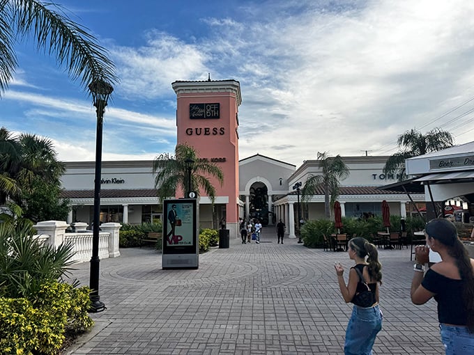 The iconic pink tower of the GUESS store stands like a fashionable lighthouse, guiding bargain hunters through a sea of designer deals.