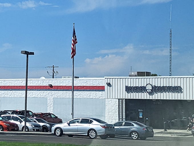 The bright white facade of Deseret Industries, with its bold red and blue stripe, shines beneath Idaho’s wide-open blue sky—a true beacon for thrift lovers.