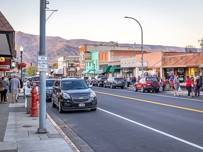 Downtown Clarkston at golden hour, where locals stroll unhurried past storefronts that haven't surrendered to chain-store uniformity. Small-town America alive and well.