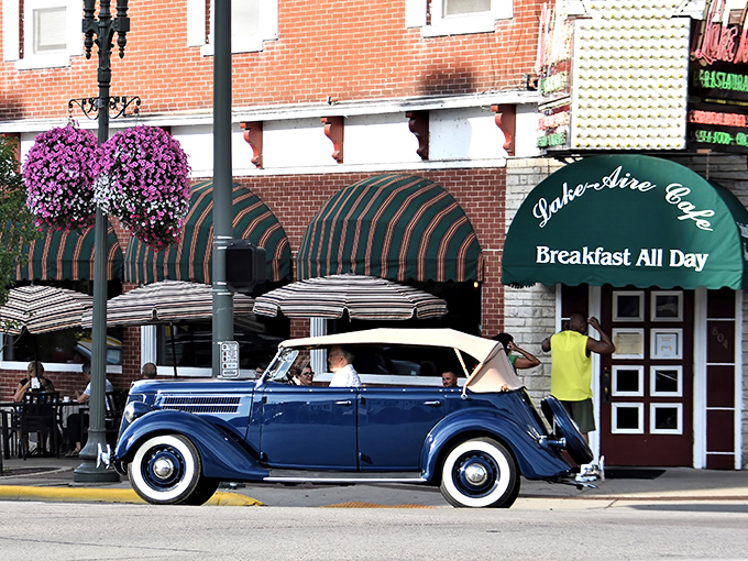 Classic Americana meets breakfast heaven – a vintage convertible cruises past Lake Aire's inviting green awnings and vibrant hanging flower baskets, promising comfort food and small-town charm.