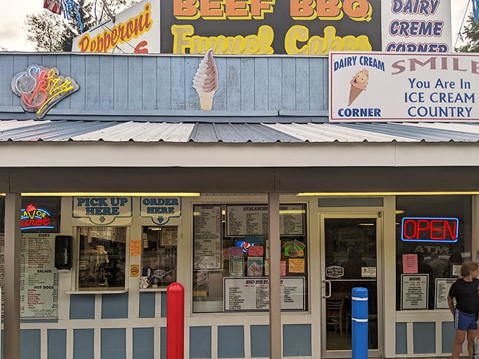 The blue-striped haven of happiness announces itself with colorful signs and pennant flags—summer incarnate in architectural form.