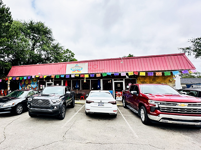 Colorful papel picado banners flutter above the parking lot, a cheerful welcome sign that promises authentic flavors await inside.