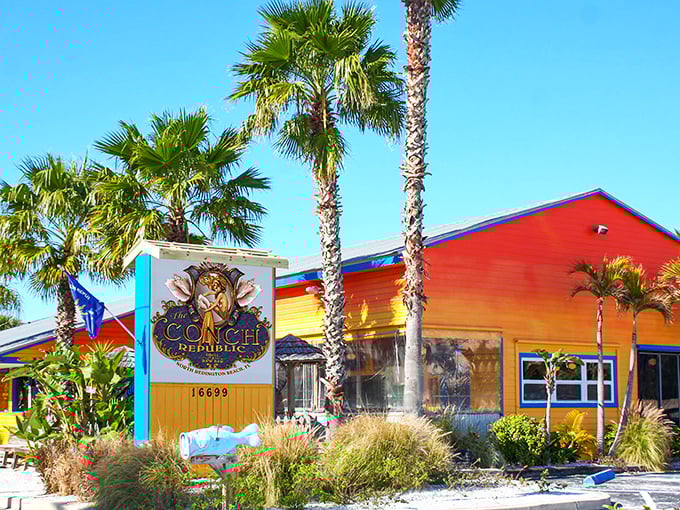 The rainbow-hued exterior of Conch Republic Grill North stands out like a tropical oasis against Florida's blue sky, palm trees swaying in welcome.