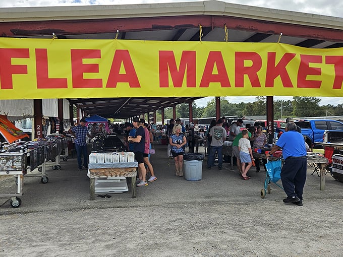 The bright yellow "FLEA MARKET" banner serves as a siren call to bargain hunters. Treasure awaits beneath this humble pavilion roof.