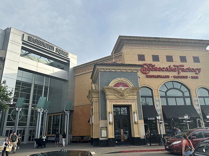 The grand entrance to Washington Square stands like a retail cathedral, with The Cheesecake Factory's golden façade promising indulgence before you've even stepped inside.