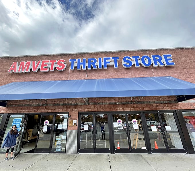 The unassuming brick exterior of AMVETS Thrift Store beckons with its bold blue signage, promising treasure hunters adventures that await just beyond those glass doors.