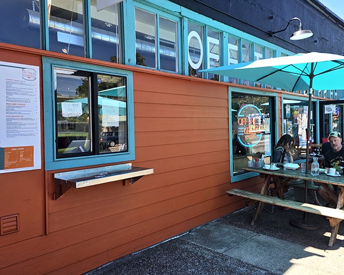The vibrant orange exterior of Off The Griddle beckons like a culinary lighthouse, complete with rustic picnic tables for Portland's rare sunny days.