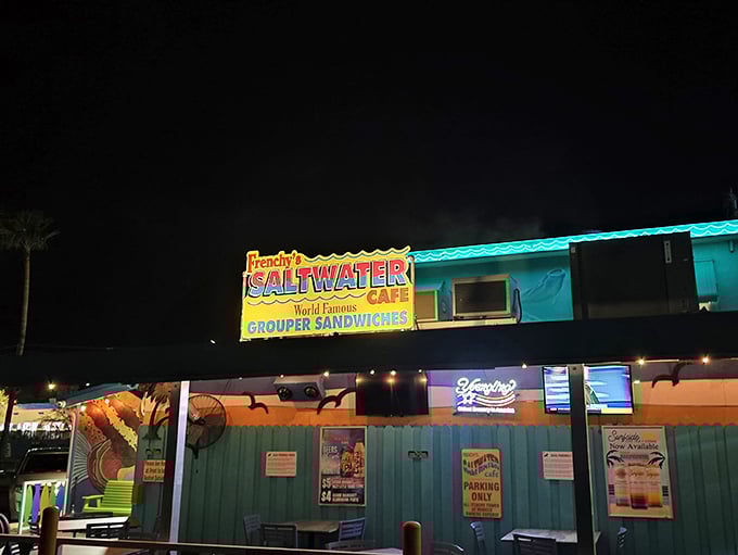 The vibrant turquoise exterior of Frenchy's Saltwater Cafe welcomes beach-goers with its colorful surfboard railings and promise of fresh seafood treasures within.