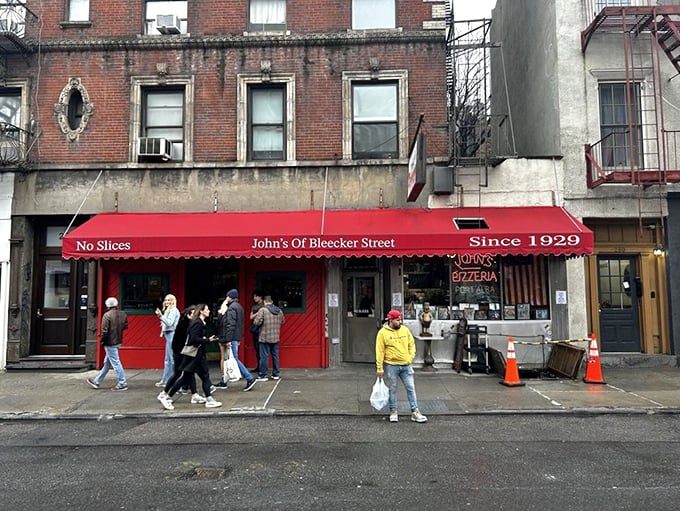 The iconic red awning of John's proudly declares "No Slices" – a battle cry that separates the pizza tourists from the true believers.