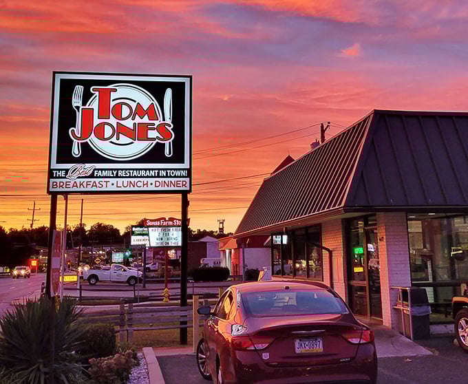 The iconic Tom Jones sign glows against a spectacular sunset, promising comfort food treasures that locals have cherished for generations.