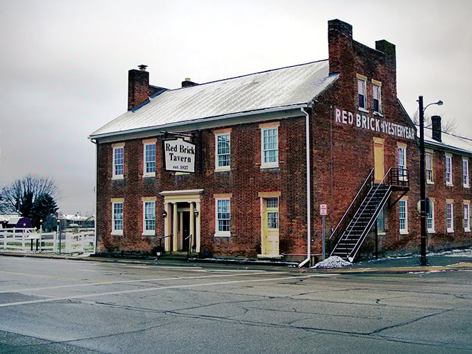 The Red Brick Tavern stands proudly along Route 40, its historic façade practically whispering tales from the 1800s while colorful flower beds add a welcoming touch.