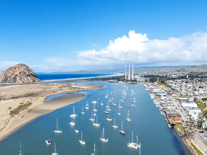 Morro Bay's iconic rock stands guard over a harbor dotted with sailboats, like nature's own lighthouse welcoming travelers to California's hidden coastal gem.