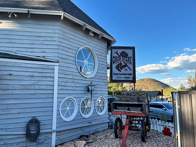 The weathered white clapboard exterior of Grub Steak whispers tales of countless memorable meals, while that vintage wagon stands guard like a time-traveling maître d'.
