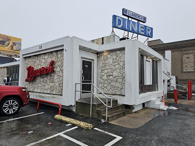 That iconic blue sign beckoning hungry travelers like a neon lighthouse – Llanerch's stone exterior says "come in, we've got what you need."