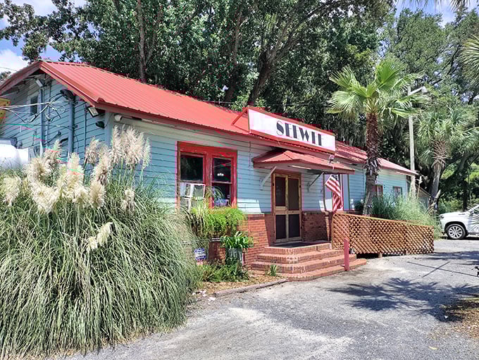 The light blue exterior with red trim stands like a coastal sentinel among the palmettos, promising seafood treasures within. No fancy facade needed when the food speaks volumes.