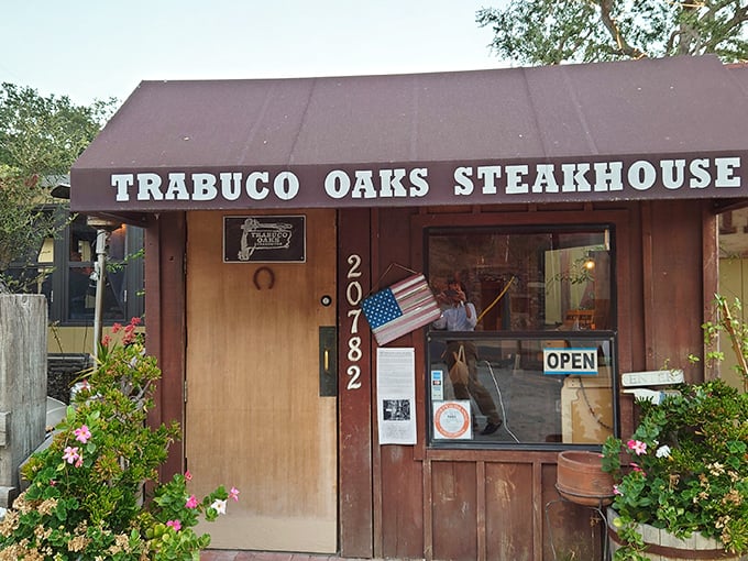 The unassuming entrance to culinary paradise – Trabuco Oaks Steakhouse stands proudly in its rustic glory, promising carnivorous delights behind that wooden door.
