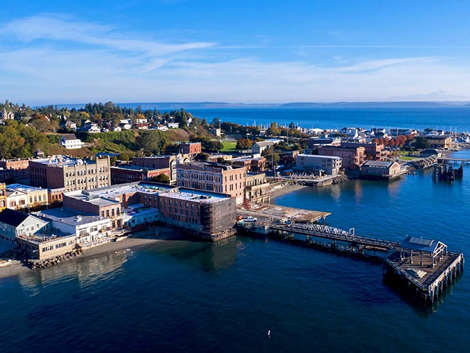 The aerial view reveals Port Townsend's perfect positioning—historic brick buildings embracing the waterfront while the residential hillside watches over everything like proud parents.
