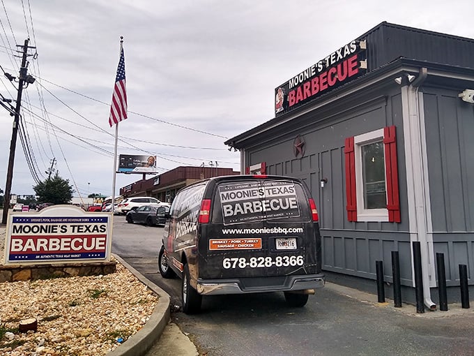 The unassuming gray exterior with bold red signage is like a secret handshake – those who know, know. BBQ paradise awaits inside.