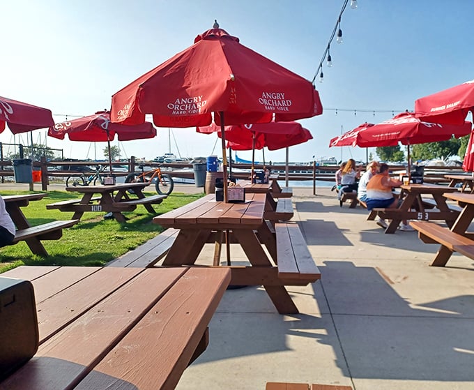 Paradise found! Red umbrellas dot the lakeside patio where wooden picnic tables invite you to linger as boats bob gently in the background.