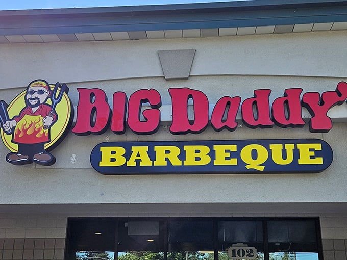 The bright red sign with its cheerful cartoon mascot promises what every BBQ pilgrim seeks: authentic smoke-kissed meats that don't need fancy surroundings to impress. 