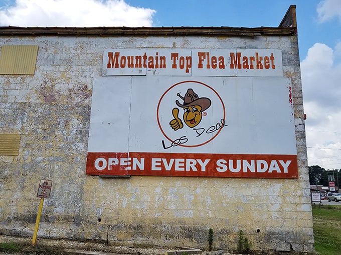 The weathered sign with its cheerful cowboy mascot stands as a beacon of Sunday treasure hunting, promising adventures that money can't buy—but bargains you can.