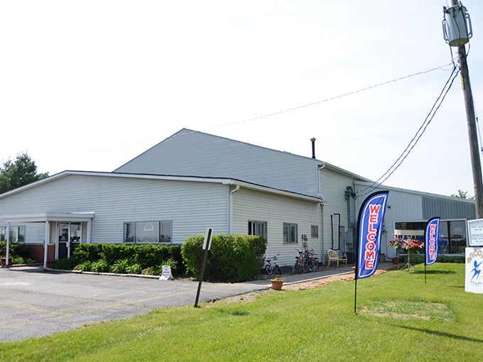 The unassuming exterior of Encore Thrift Store stands like a treasure chest waiting to be opened, those blue flags signaling "bargain hunters welcome!"