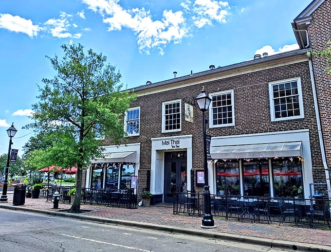 The charming brick façade of Mai Thai beckons from Old Town Alexandria's historic streets, promising culinary adventures behind those welcoming red awnings.