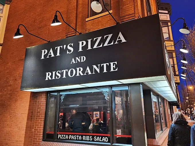 The classic brick façade and illuminated sign of Pat's Pizza & Ristorante stands as a beacon for pizza lovers navigating Lincoln Avenue after dark.