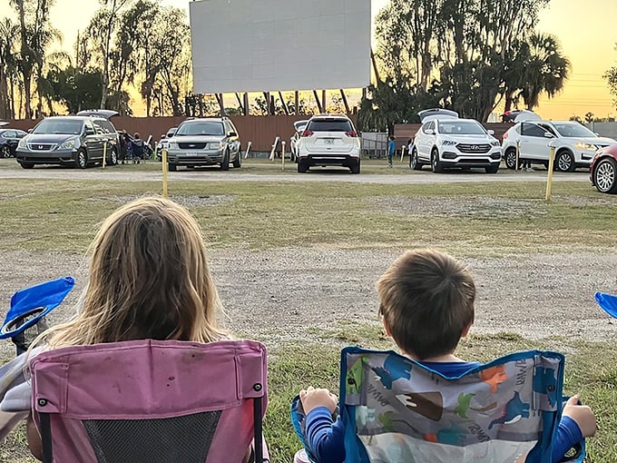 Cars lined up at dusk, their silhouettes framed against the massive white screen—cinema's most honest relationship with the Florida sunset.
