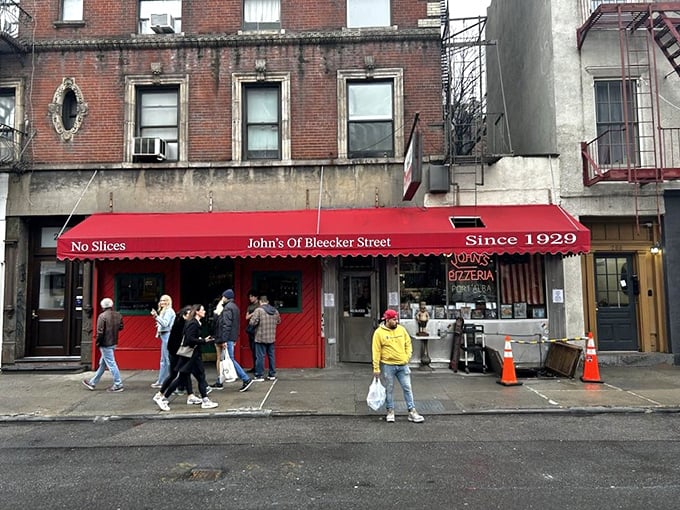 The iconic red awning of John's proudly declares "No Slices" – a battle cry that separates the pizza tourists from the true believers.