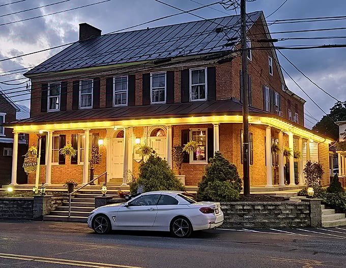 Twilight transforms this historic brick tavern into a beacon for hungry travelers, its warm porch lights promising comfort food salvation after a long day's journey.